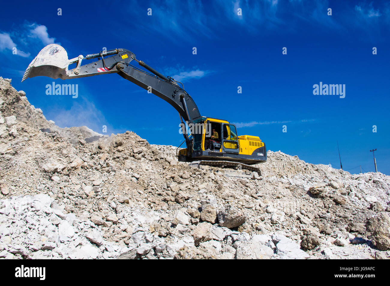 the excavator digging clay on blue sky background Stock Photo - Alamy