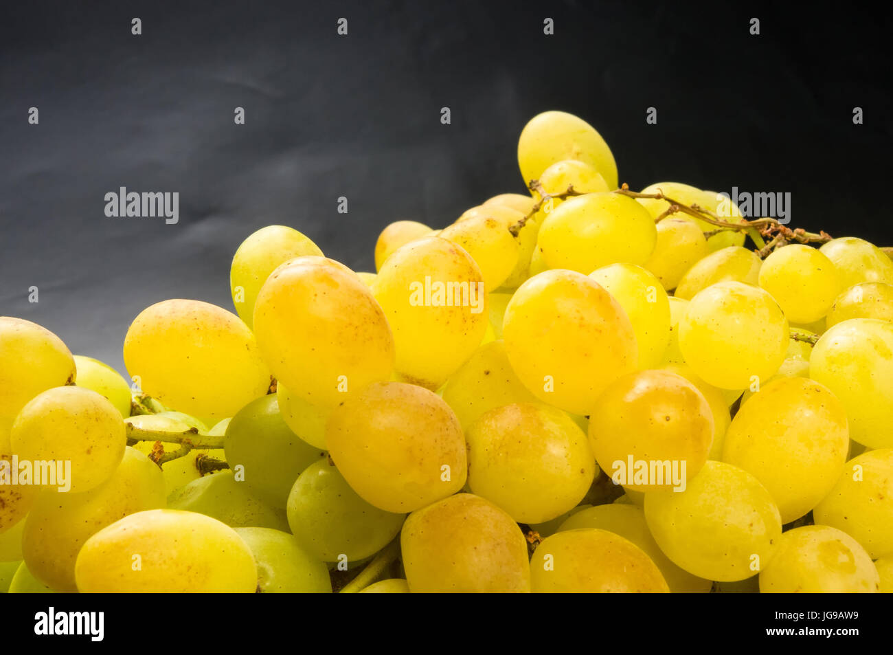 Large grapes cluster amber color on black background Stock Photo - Alamy