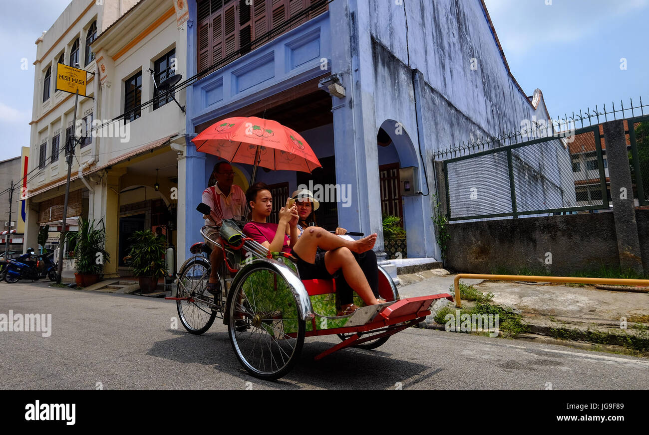 Tourists take a tour by cycle-taxi in Georgetown, Penang, Malaysia ...