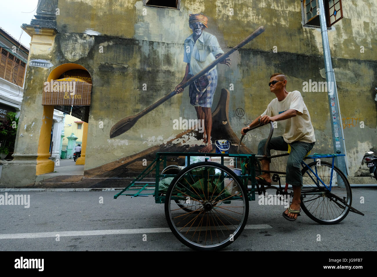 A Chinese man rides his bike past a huge wall mural in Georgetown, Penang, Malaysia Stock Photo ...