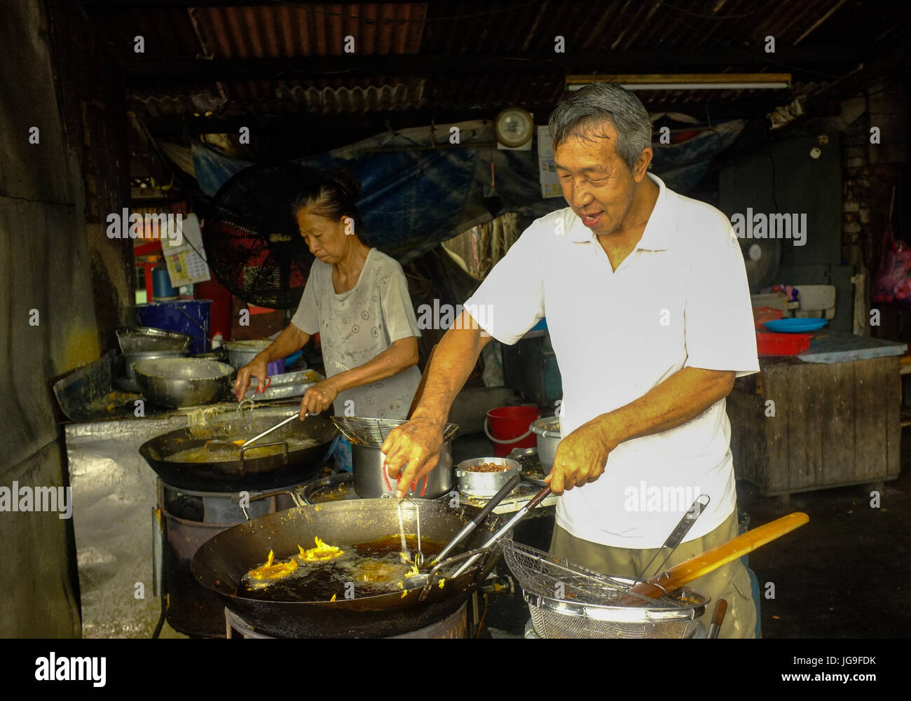 Two cooks stir fry Chinese food at a restaurant in Georgetown, Penang ...