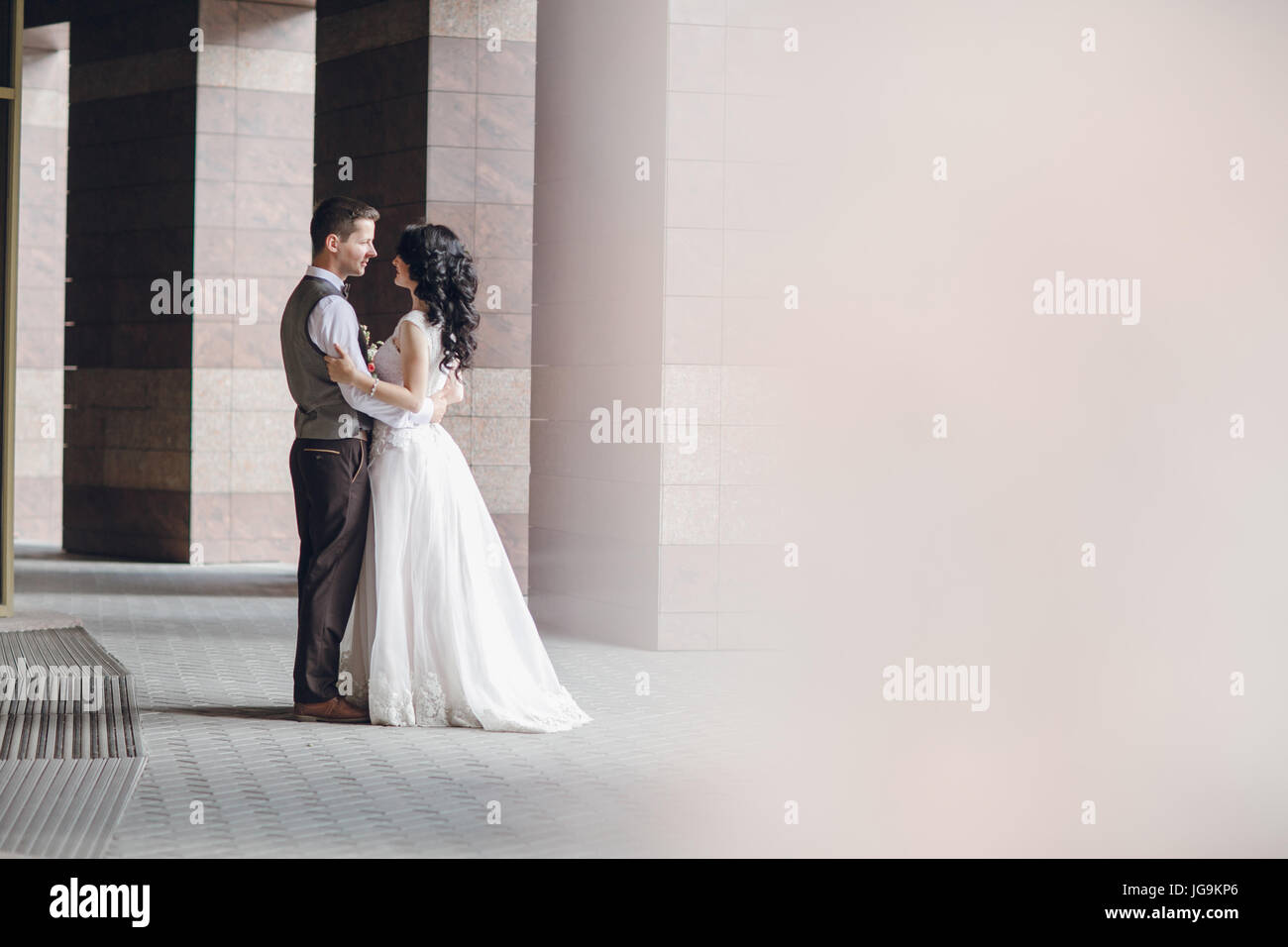 bride and groom stand near tall columns Stock Photo - Alamy