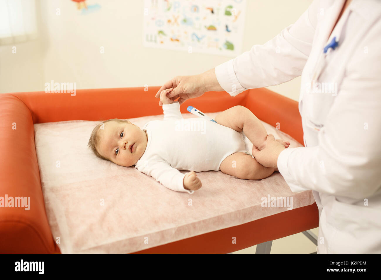 Baby lying on a couch while doctor is measuring it temperature Stock ...