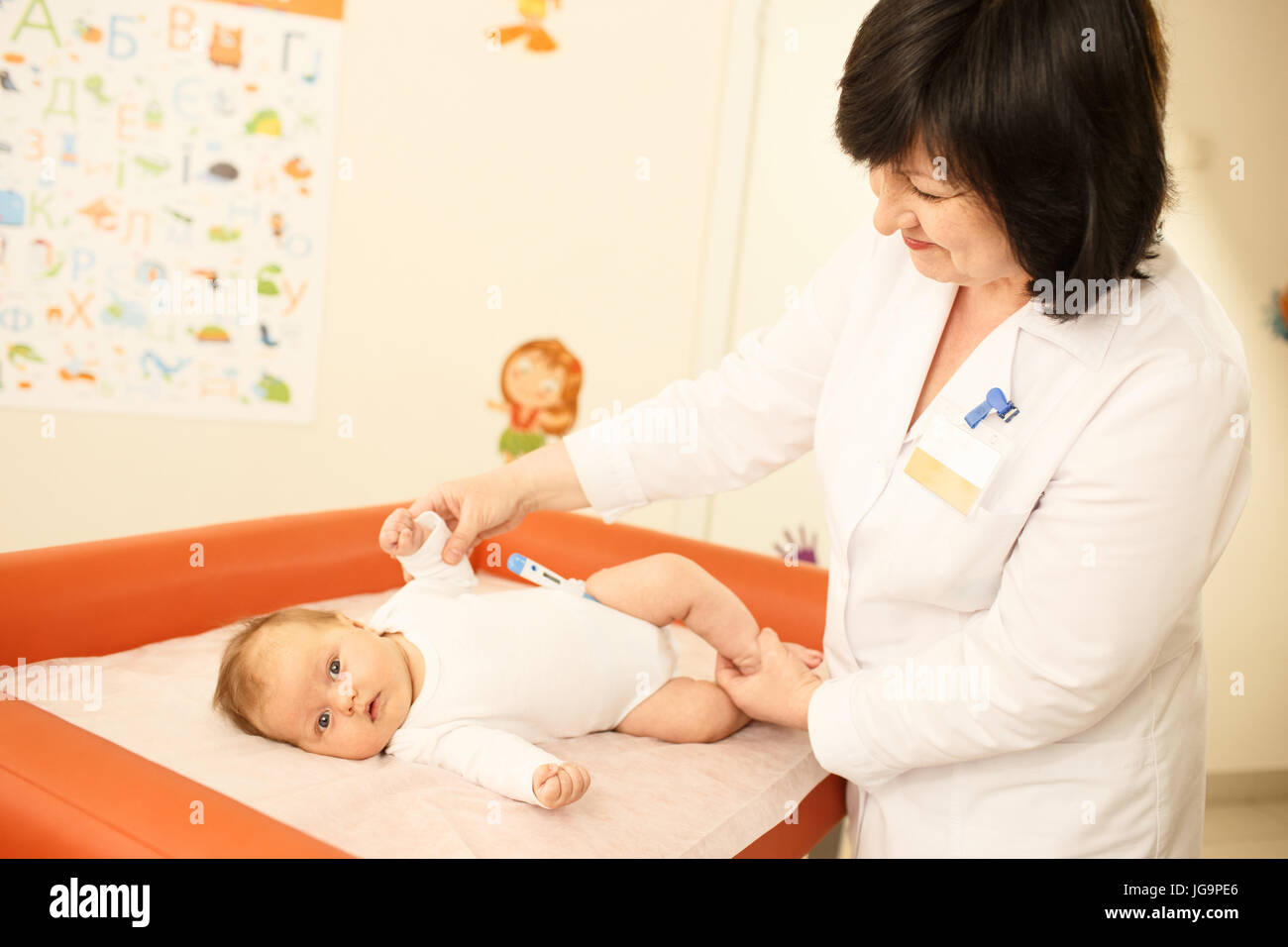Smiling doctor with baby on a couch Stock Photo - Alamy