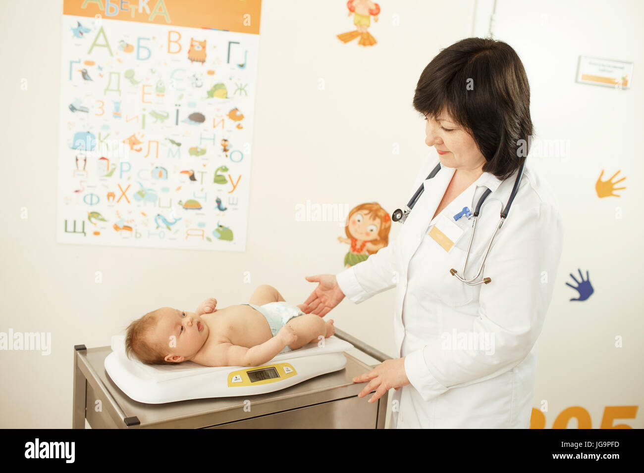 Doctor looking at a baby while it's lying on weighing-machine Stock ...