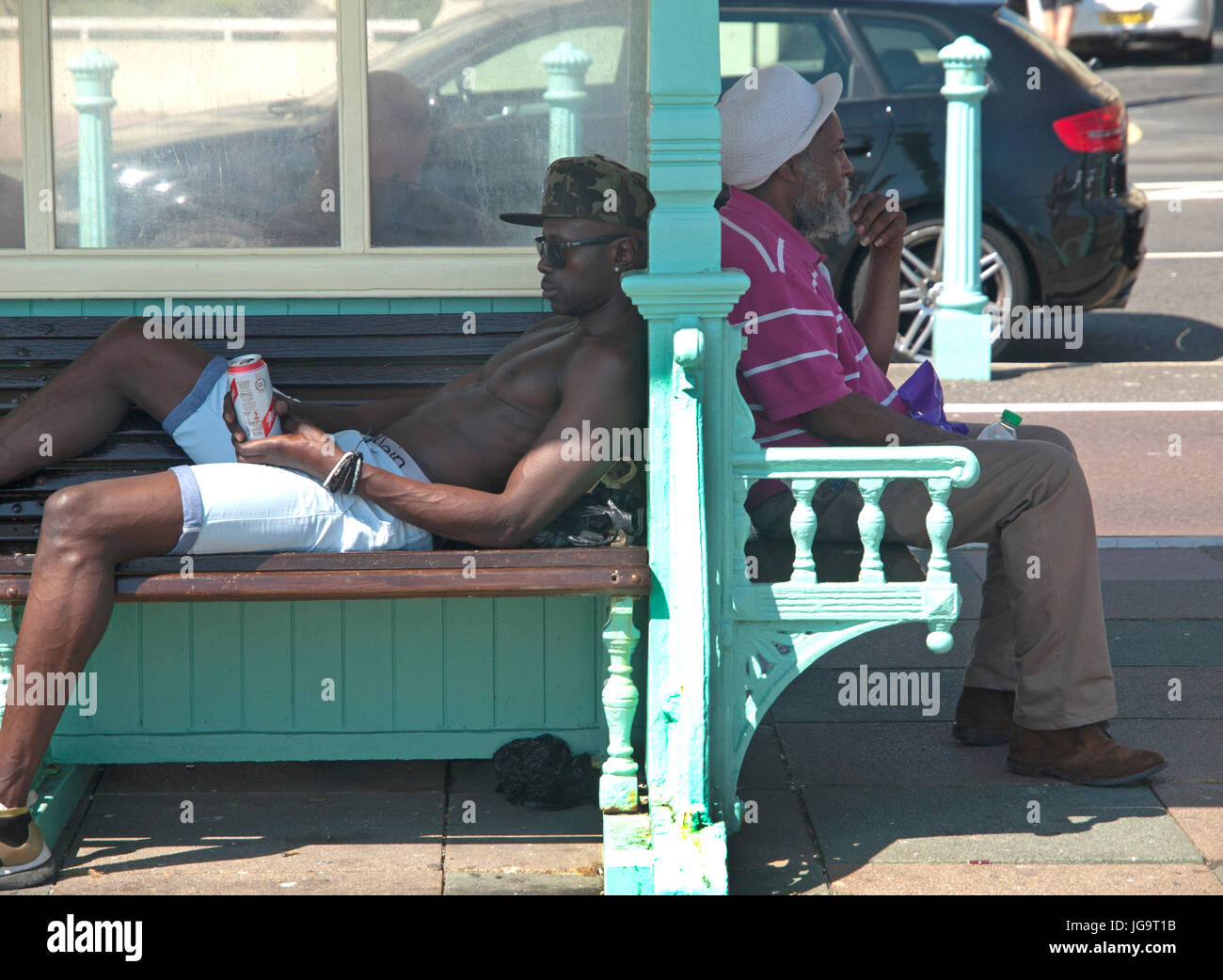Seeking shade from a seafront shelter in Brighton Stock Photo - Alamy