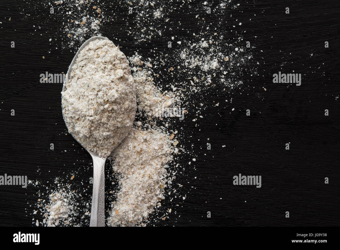 Spoonful of flour on black wooden background Stock Photo - Alamy