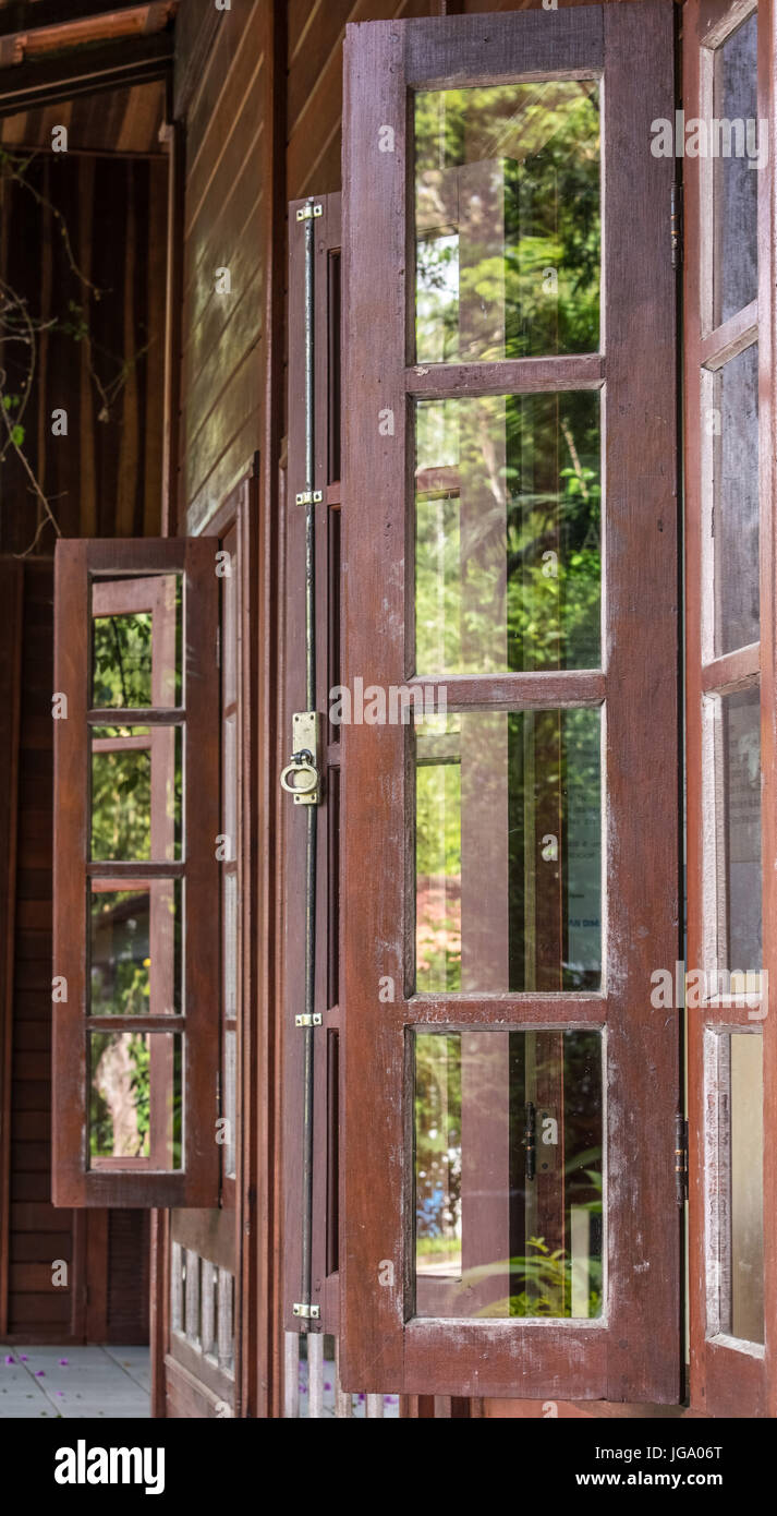 Open wooden windows on front porch with reflecting trees on glass ...