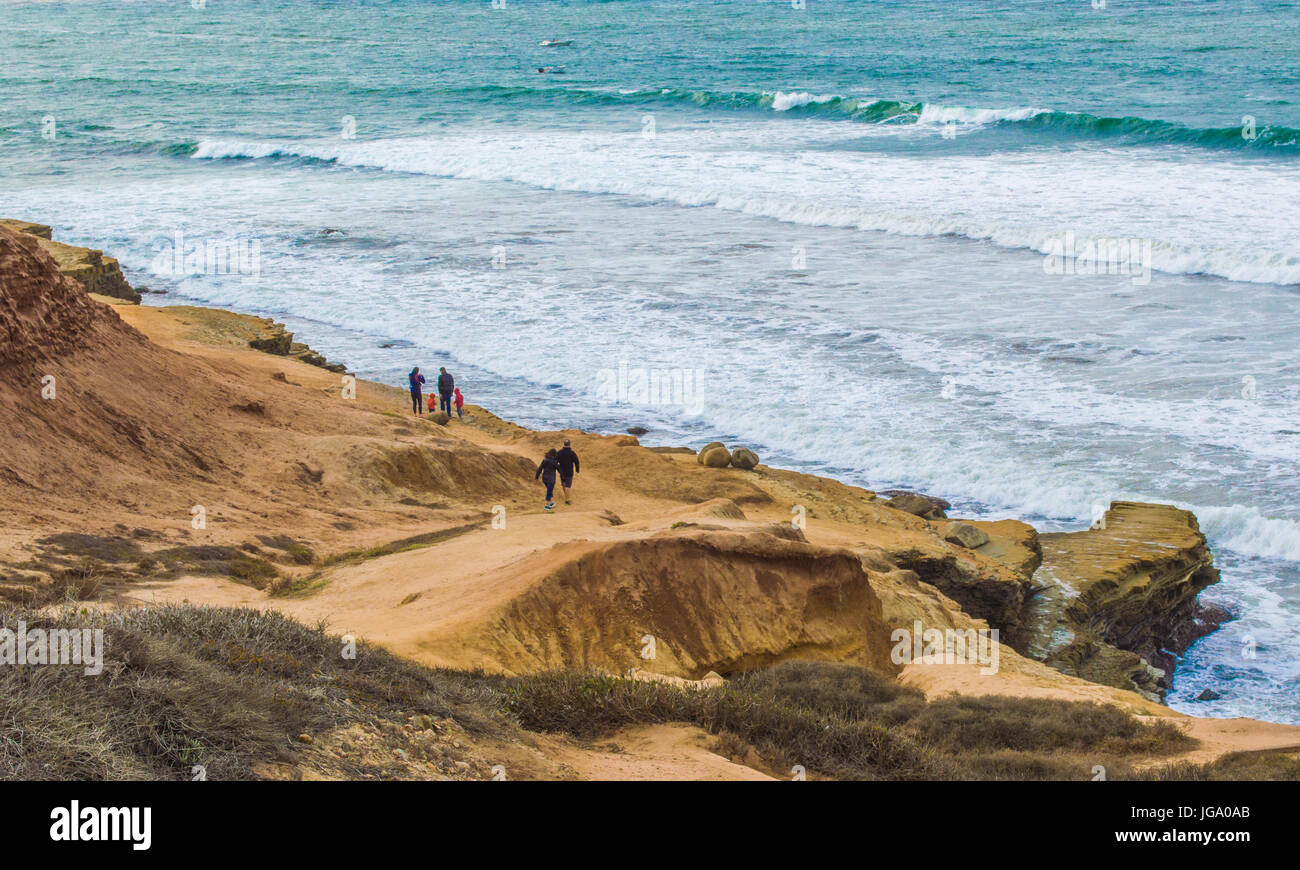 hikers on rocky shale cliffs at Pacific Ocean in San Diego, California ...