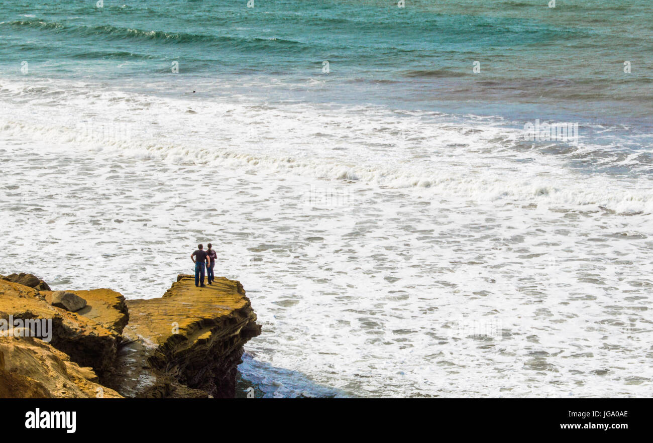 Two people standing on a shale cliff at the Pacific Ocean in San Diego ...