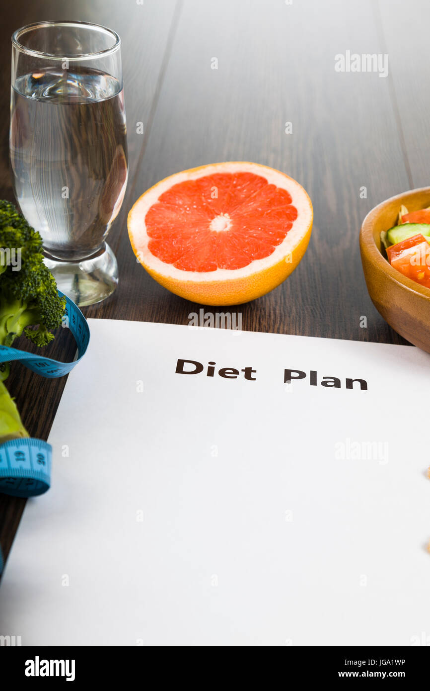 Food and sheet of paper with a diet plan on a dark wooden table ...