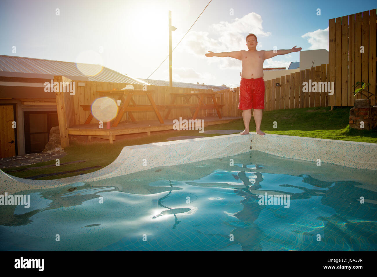 asian man wearing red shorts opened arms standing beside swim pool ...