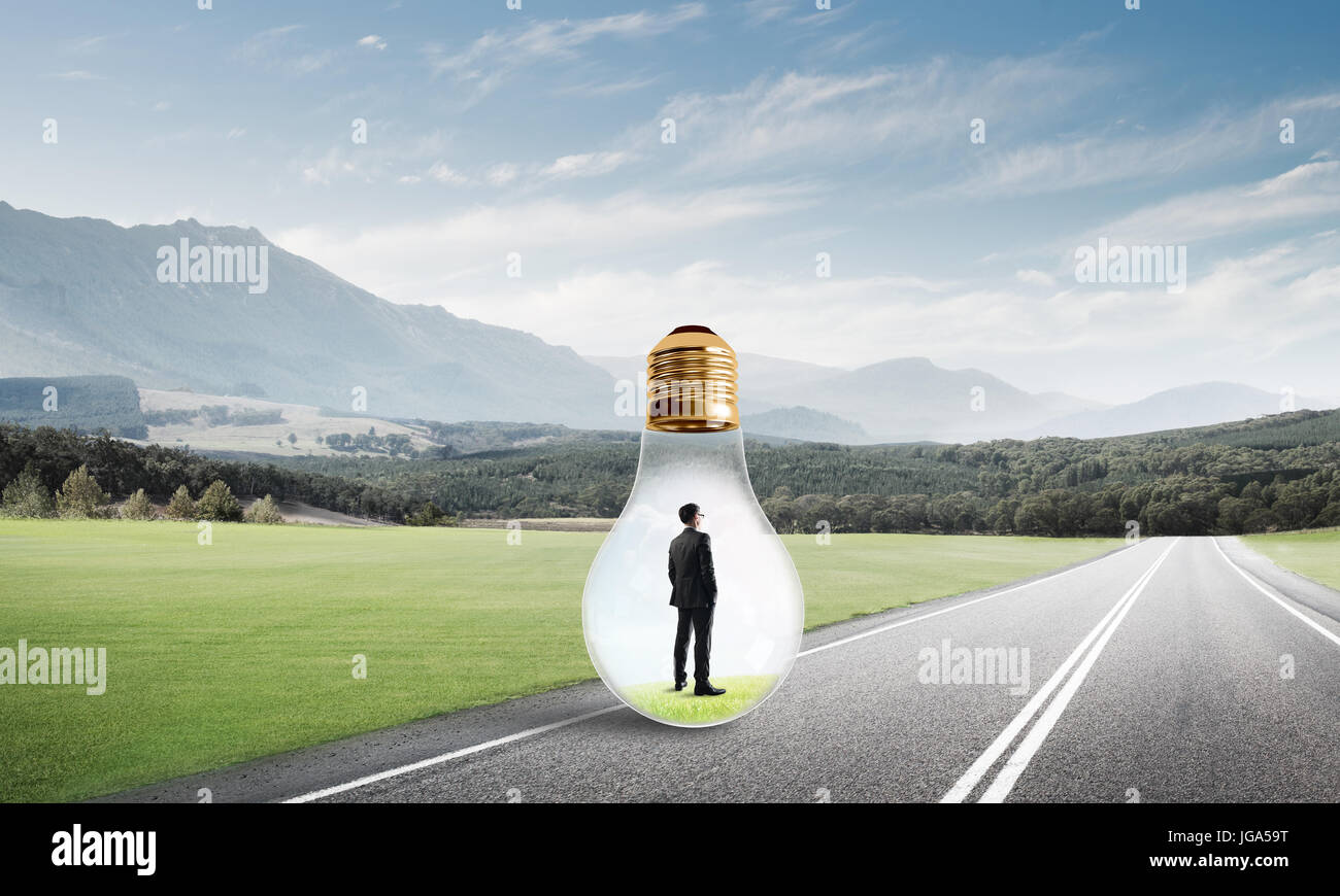 Young businessman trapped inside of light bulb on asphalt road Stock ...