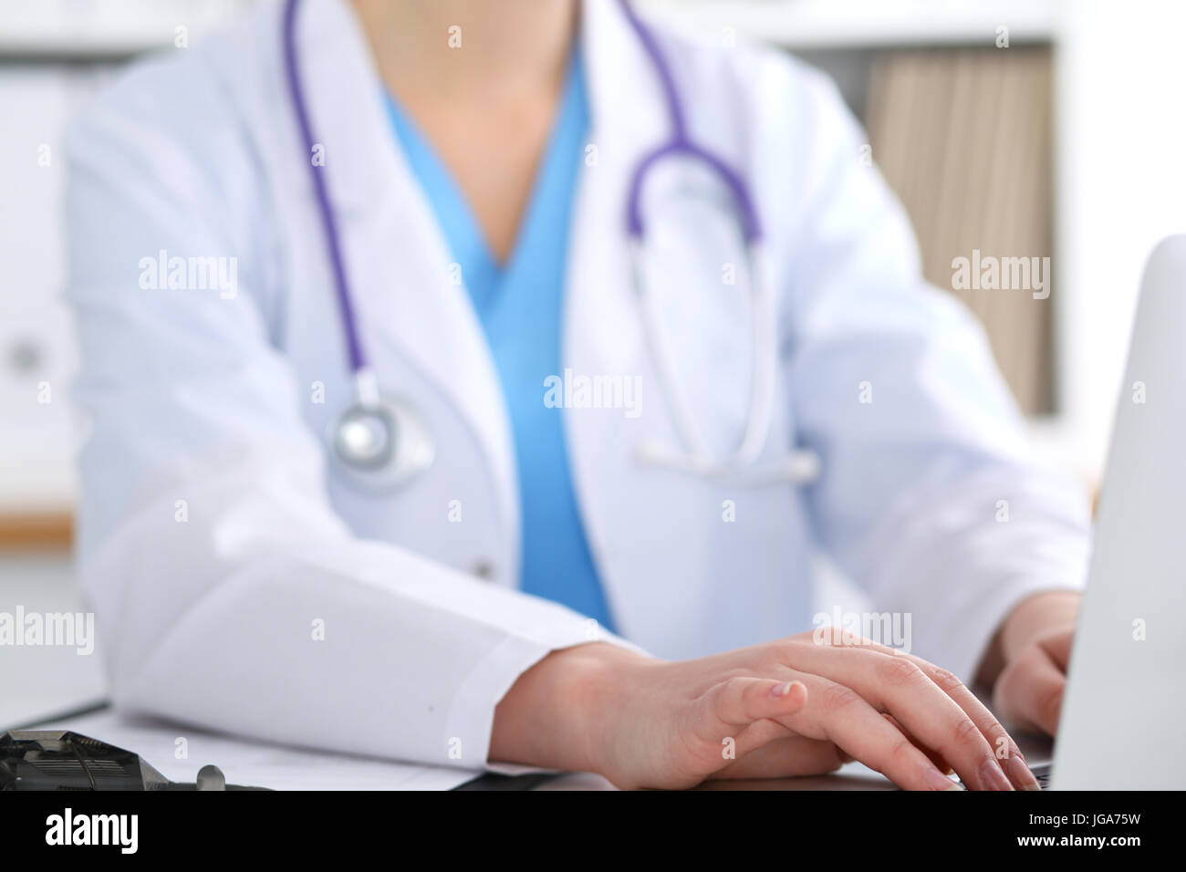 Close up of unknown female doctor typing on laptop computer while ...