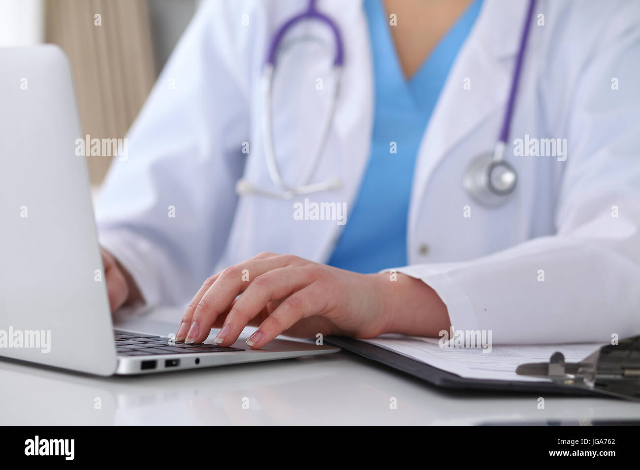 Close up of unknown female doctor typing on laptop computer while ...