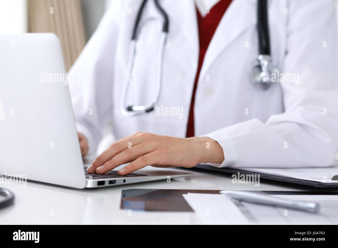 Close up of unknown female doctor typing on laptop computer while ...