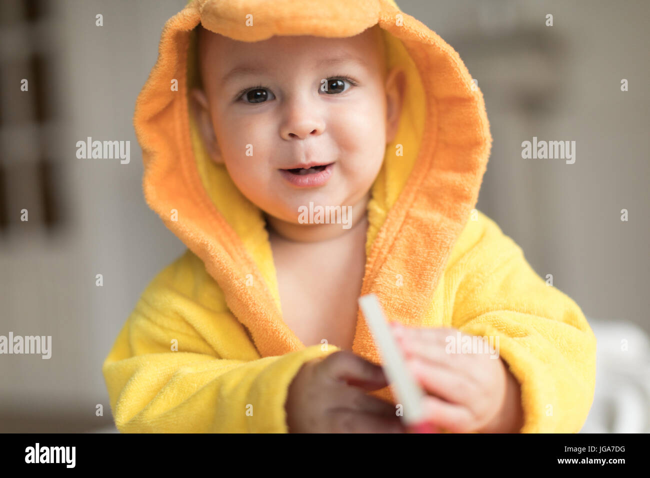 Happy baby boy in yellow robe posing on bed Stock Photo - Alamy