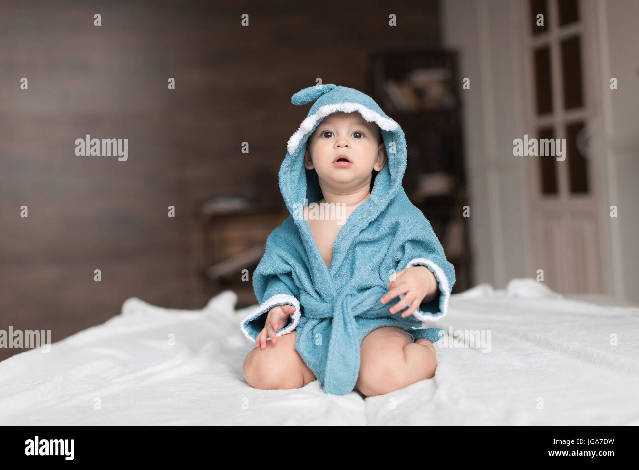 Happy baby boy in blue robe posing on bed Stock Photo - Alamy