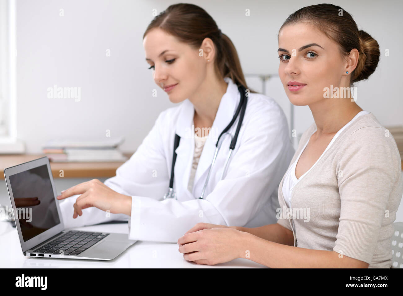 Doctor and patient sitting at the desk. Physician pointing into laptop ...