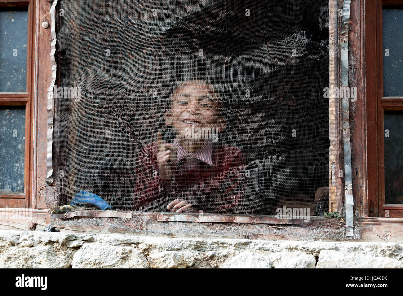 Boy looking though wire window in Ladakh Stock Photo - Alamy