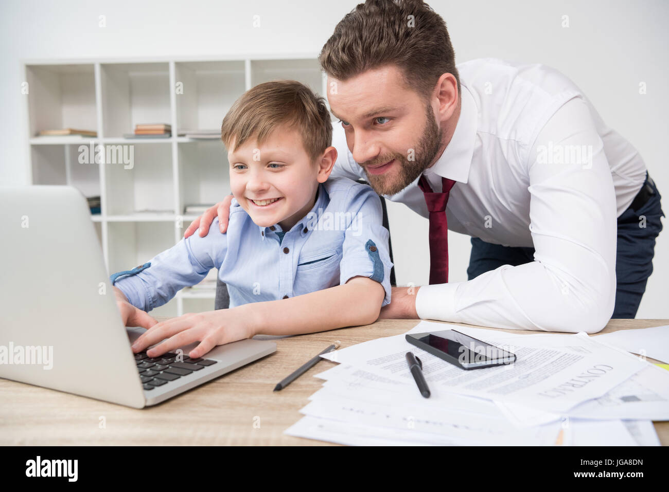 Businessman playing on laptop with his son Stock Photo - Alamy