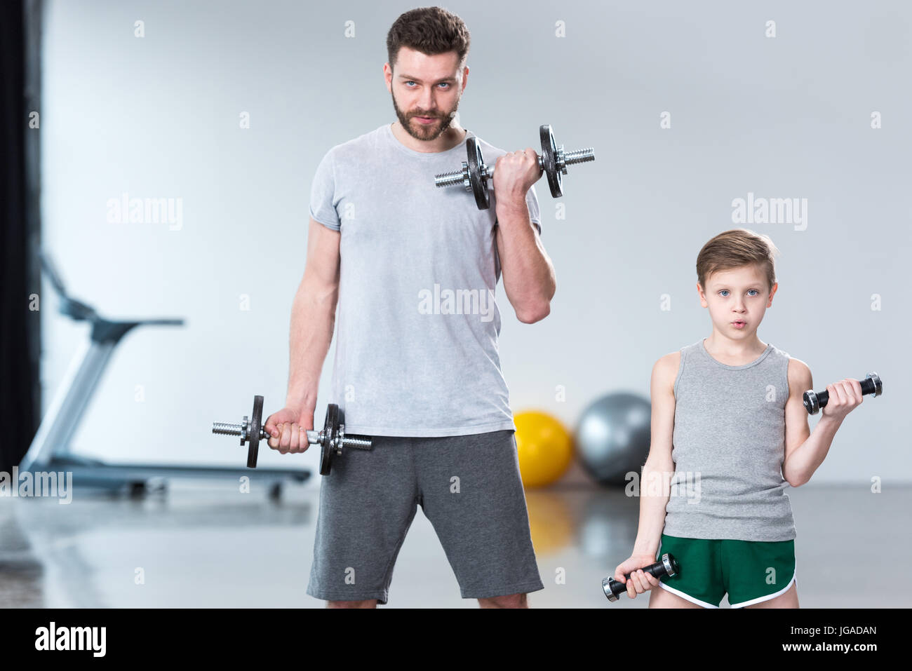 Boy training with dumbbells together with coach at fitness center Stock ...