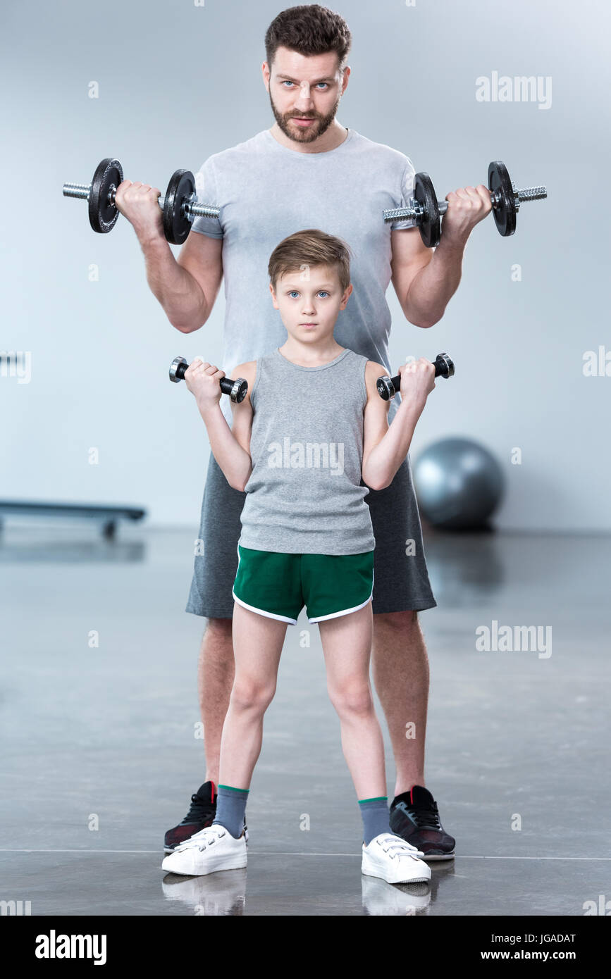Boy training with dumbbells together with coach at fitness center Stock ...