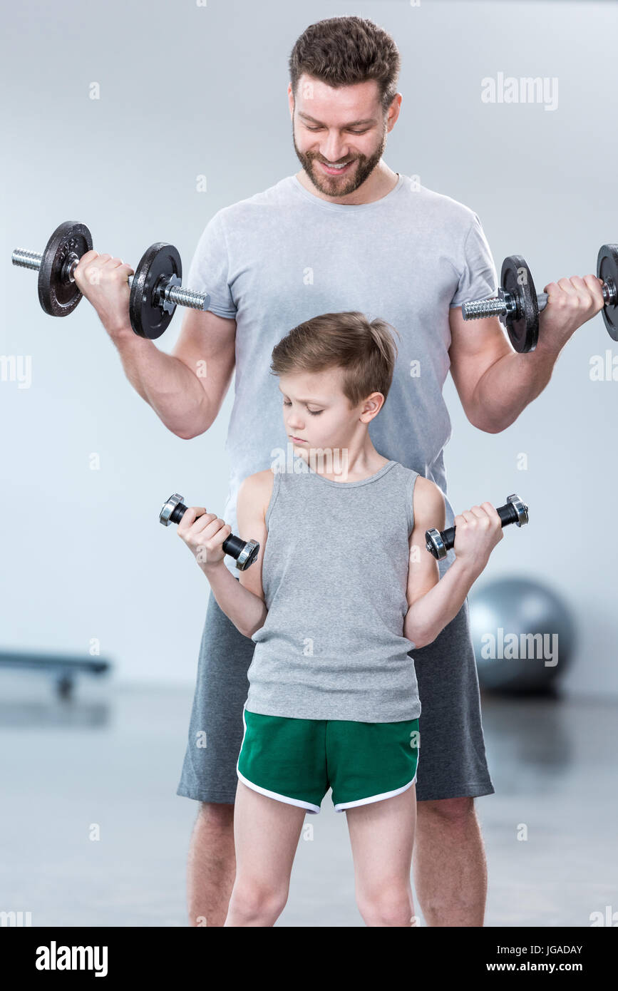 Boy training with dumbbells together with coach at fitness center Stock ...
