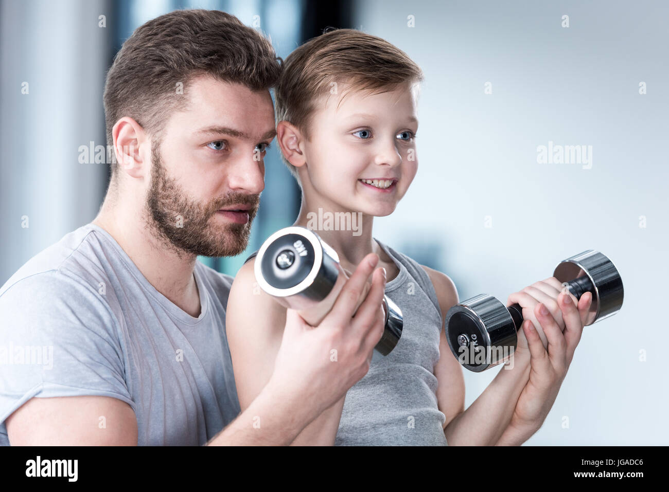 Boy training with dumbbells together with coach at fitness center Stock ...