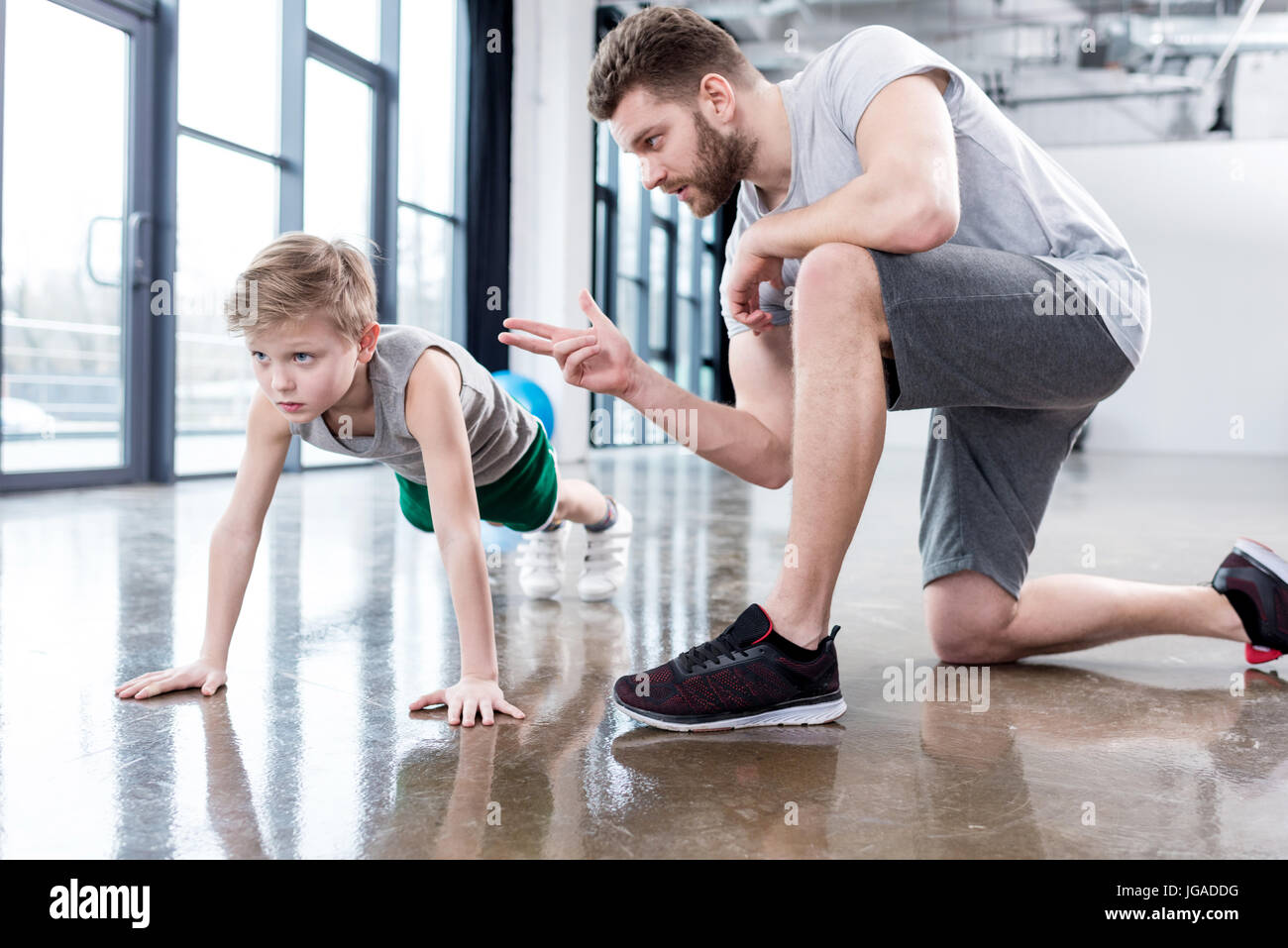 Boy doing push ups with coach at fitness center Stock Photo - Alamy