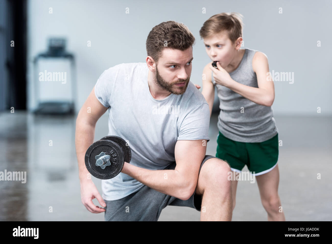 Boy coach training man exercising with dumbbell Stock Photo - Alamy