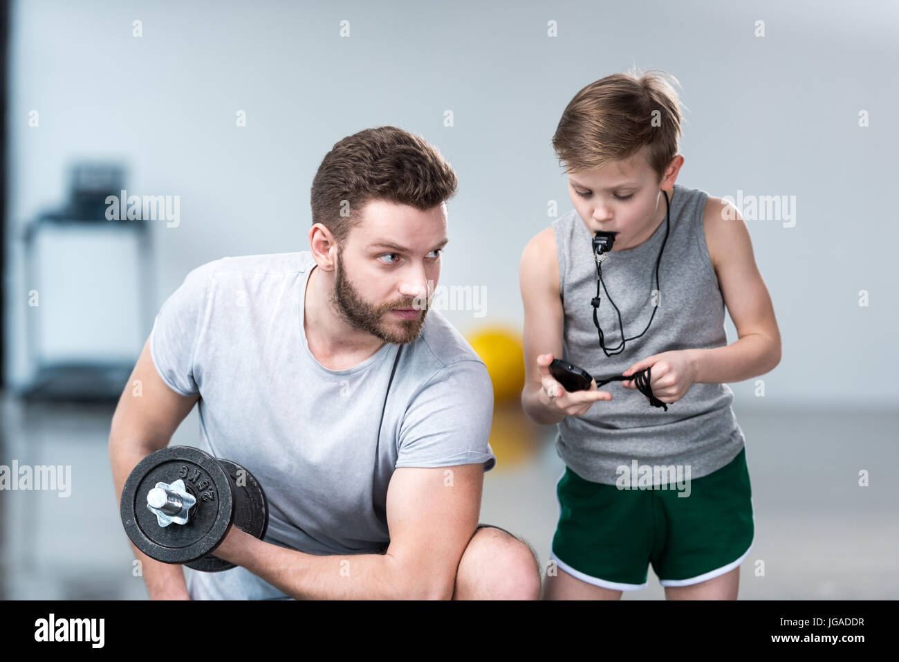 Boy coach training man exercising with dumbbell Stock Photo - Alamy