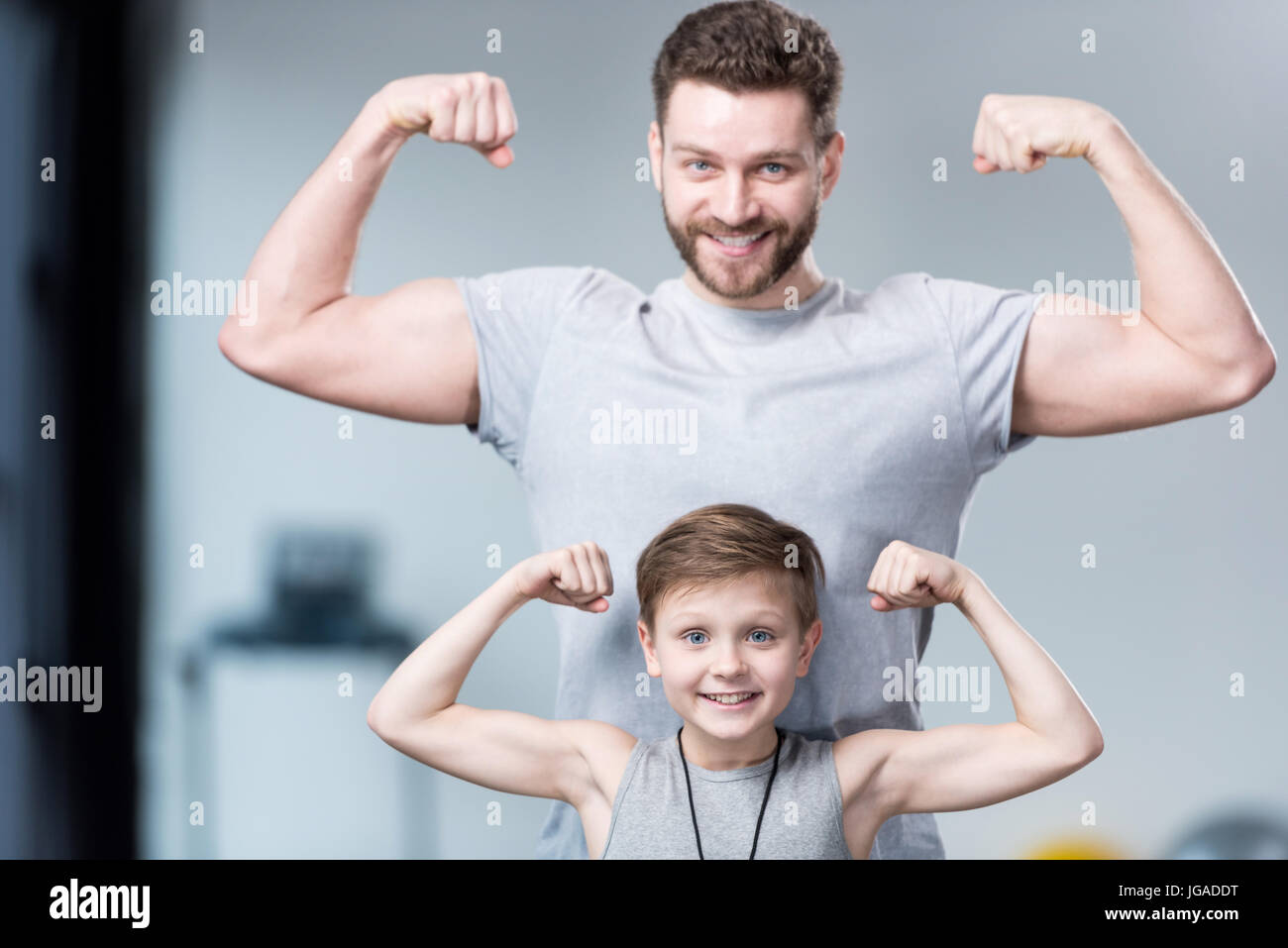 Boy with young man, his trainer or father showing muscles Stock Photo ...