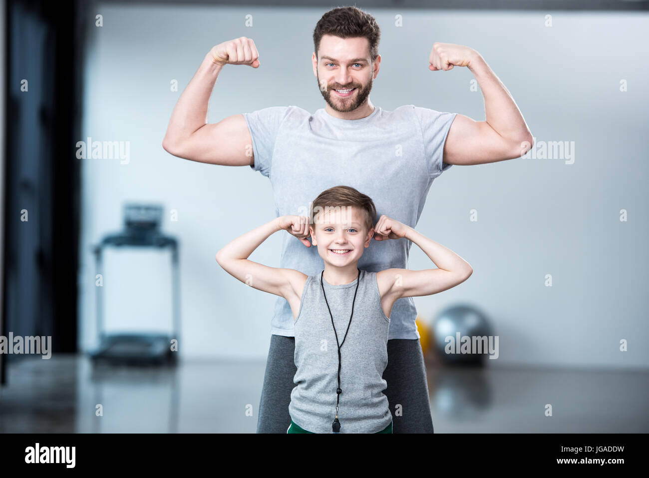 Boy with young man, his trainer or father showing muscles Stock Photo ...
