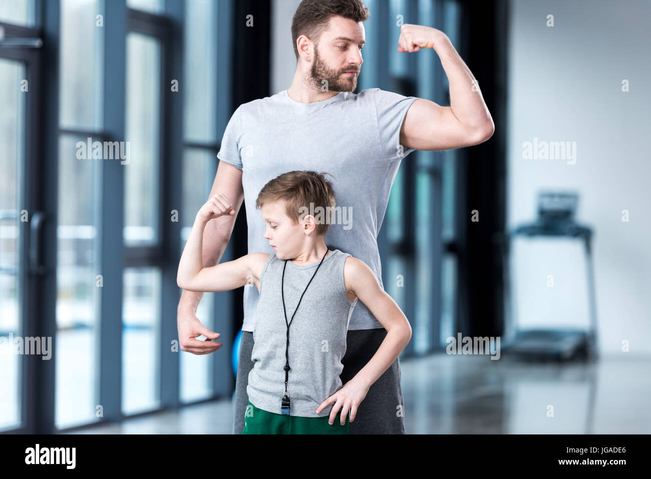 Boy with young man, his trainer or father showing muscles Stock Photo ...