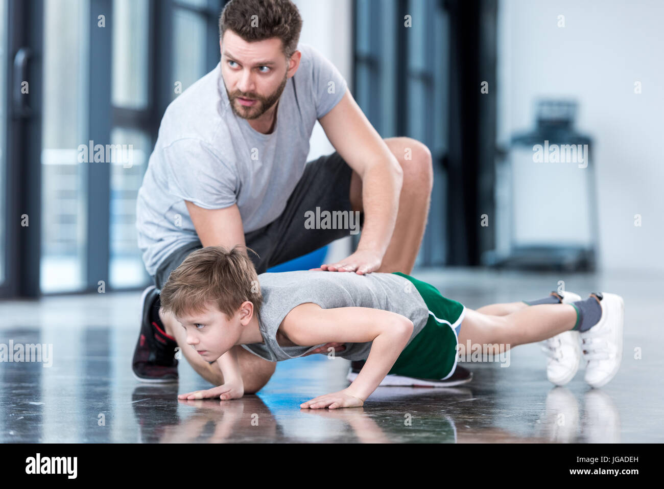 Boy doing push ups with coach at fitness center Stock Photo - Alamy