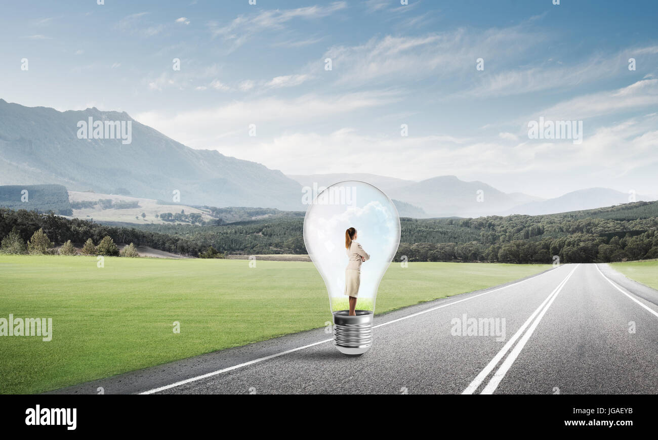 Young businesswoman trapped inside of light bulb on asphalt road Stock ...