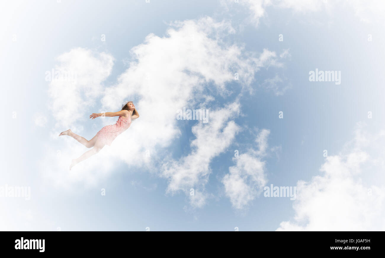 Young woman flying high in blue sky Stock Photo - Alamy