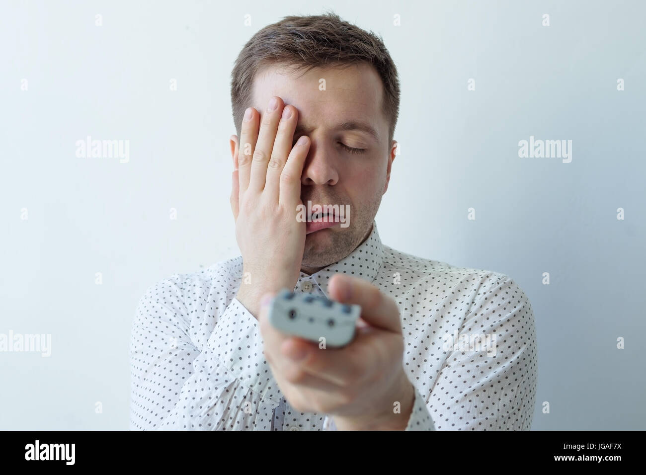 Bored man watching tv and zapping closing face with hand Stock Photo ...