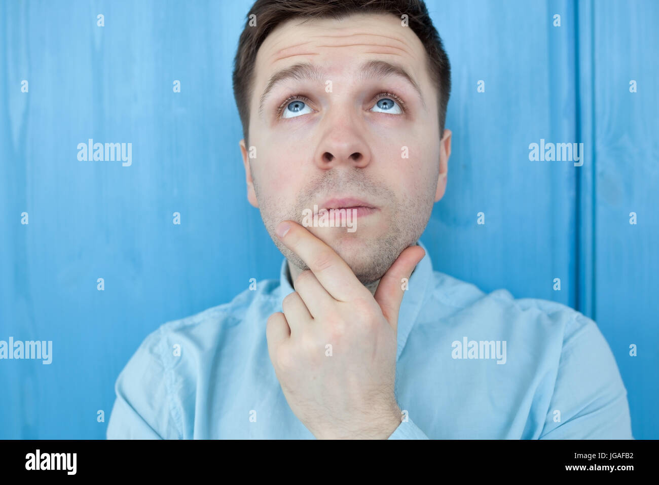 Caucasian thoughtful young man standing by the blue woodenwall Stock ...