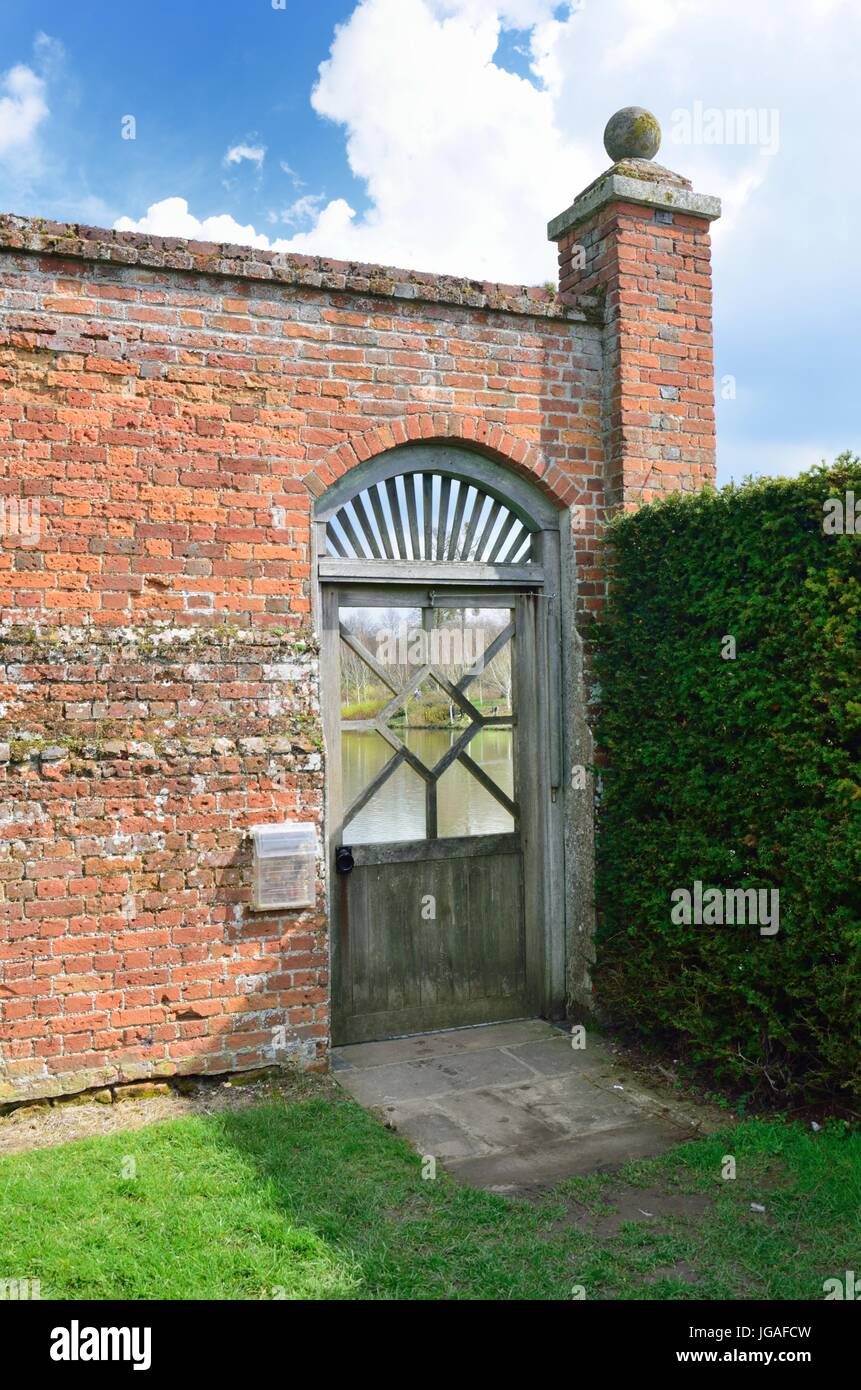 Wooden garden gate with red brick wall Stock Photo - Alamy
