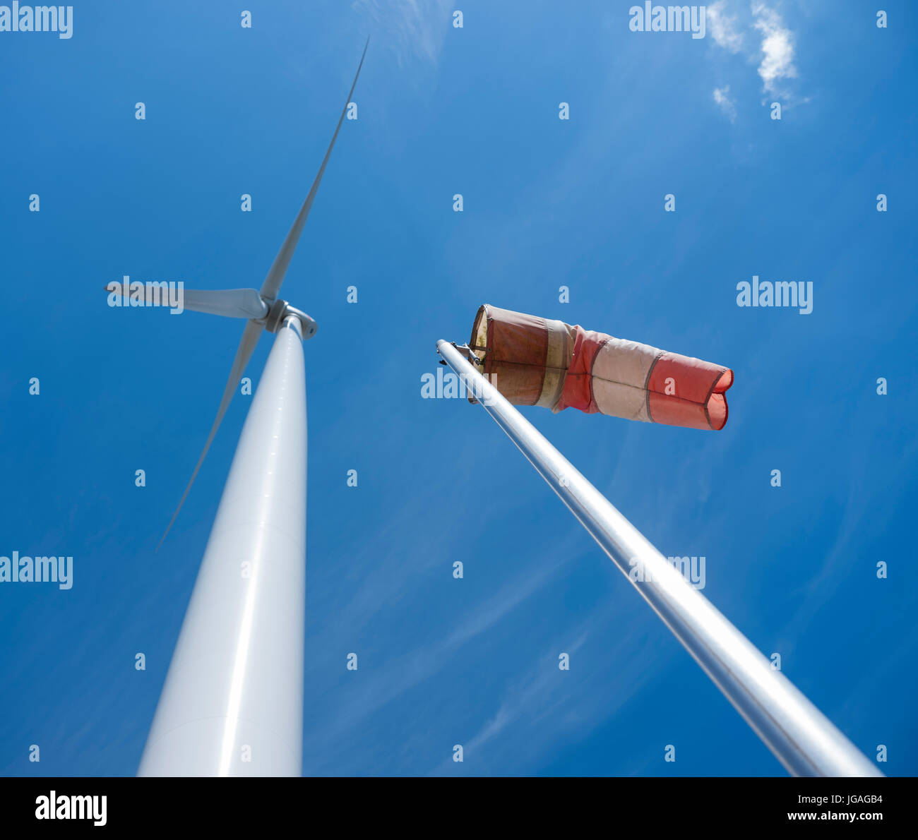 red and white windbag and wind turbine against background of blue sky ...