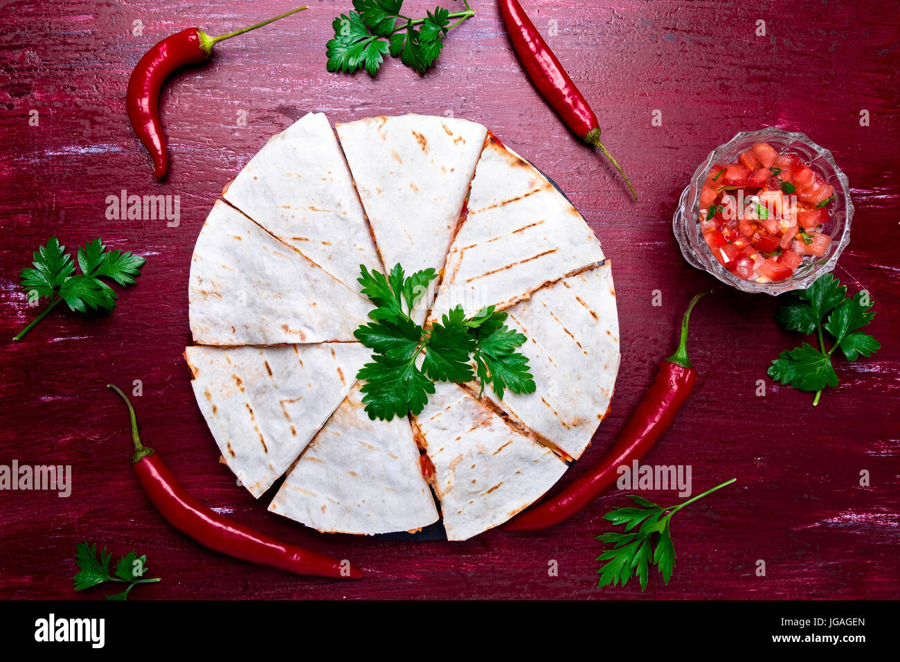 Mexican quesadilla with salsa on black slate stone plate on red wooden ...