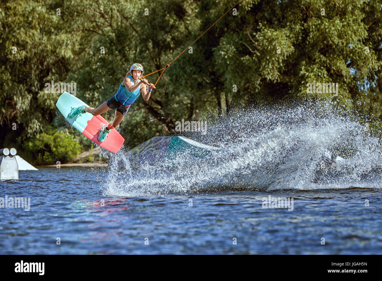 Professional sportswoman in training on wakeboarding. She jumps on the ...