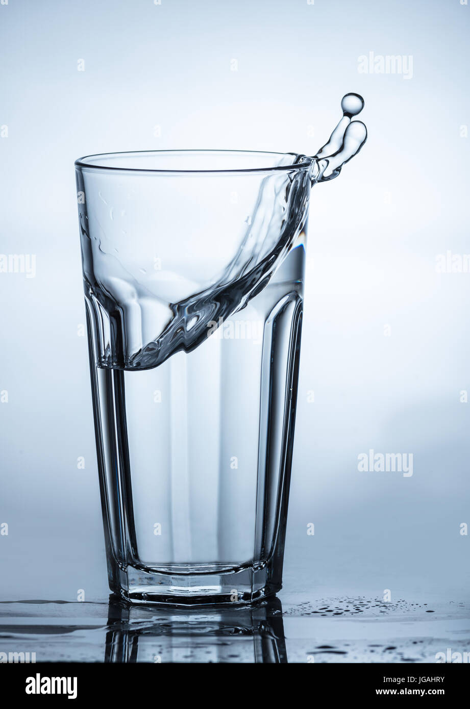 water splashing out of a glass on blue background Stock Photo - Alamy