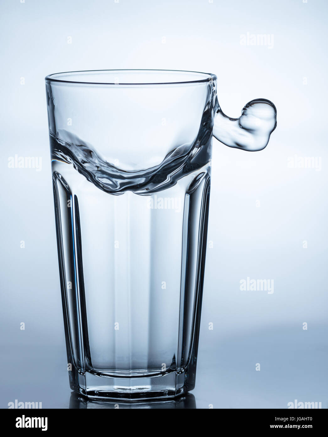 water splashing out of a glass on blue background Stock Photo - Alamy