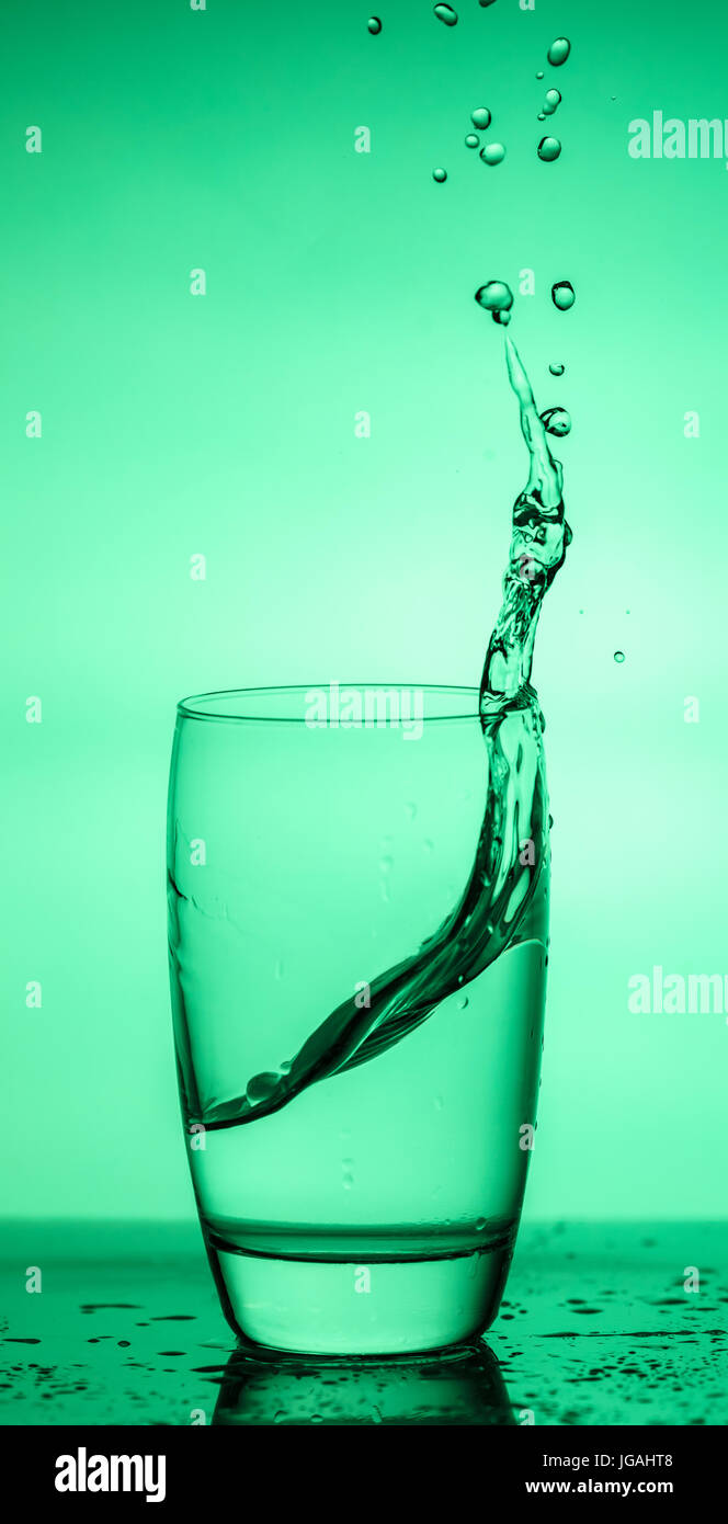 water splashing out of a glass on green background Stock Photo - Alamy