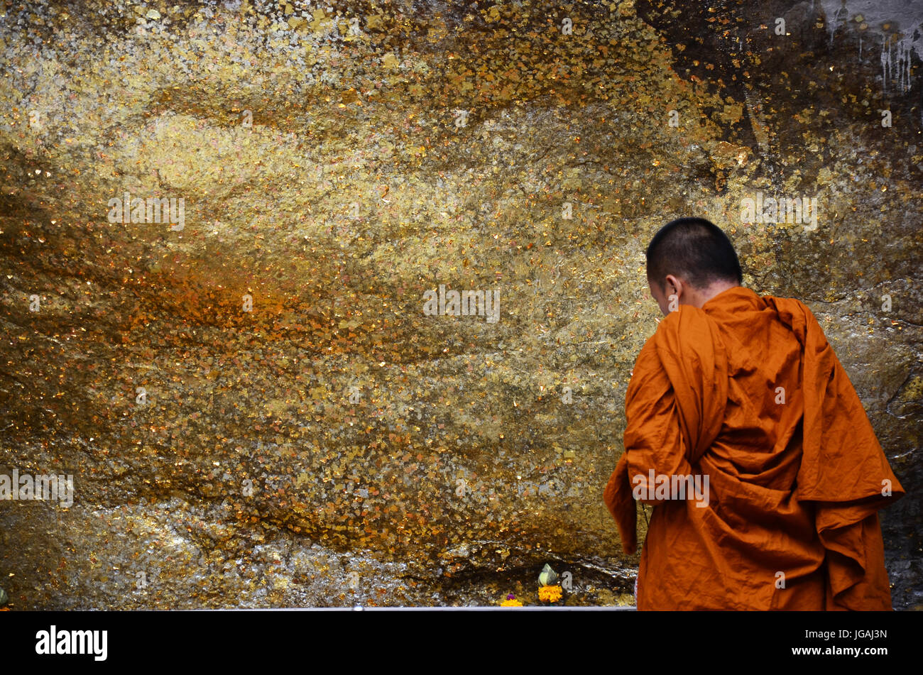 Monk respect praying and gild cover with gold leaf at Lord Buddha image ...