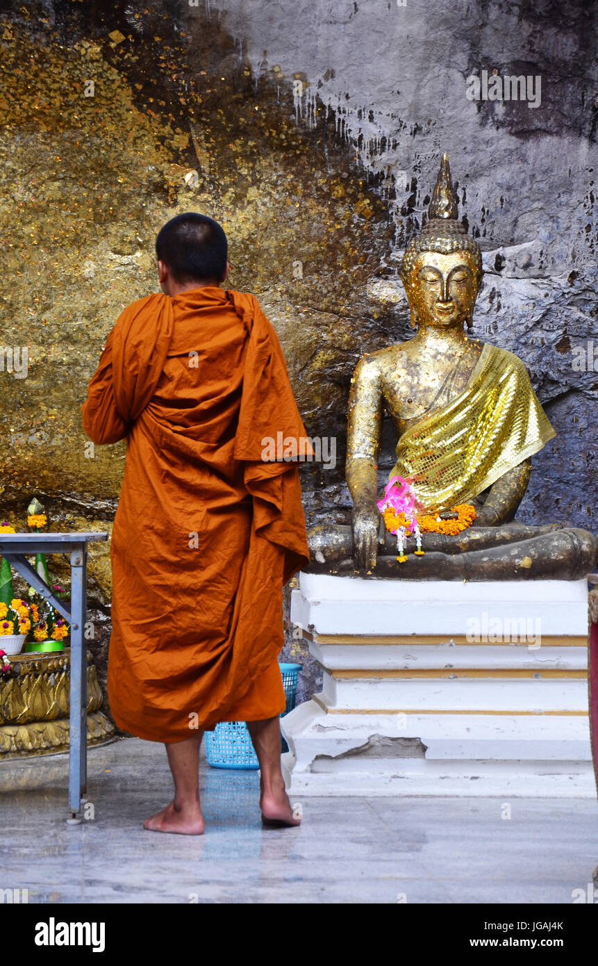 Monk respect praying and gild cover with gold leaf at Lord Buddha image ...