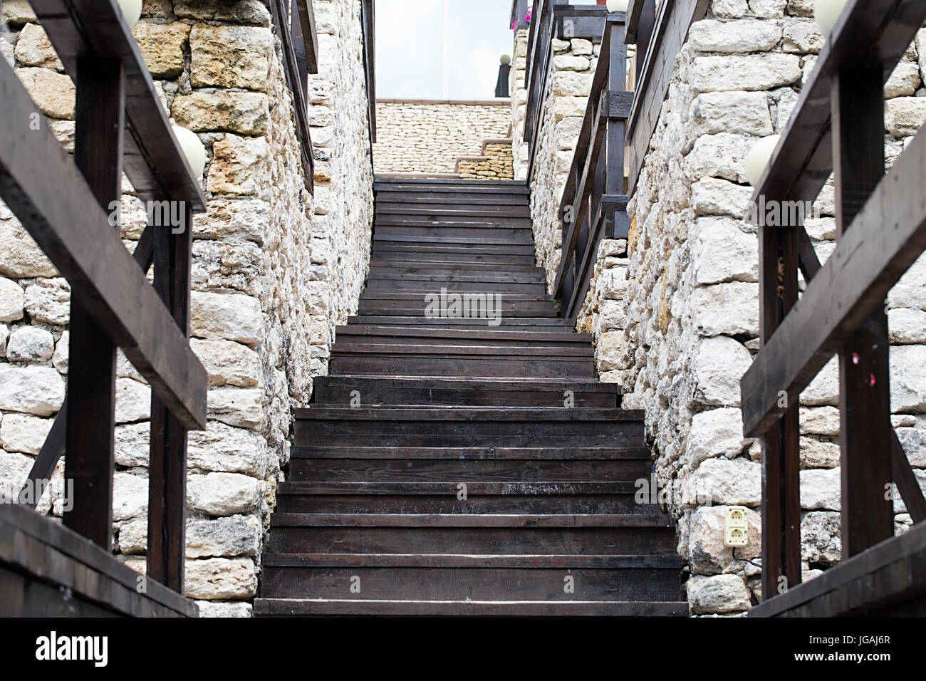 Wooden stairs at a castle. Steps on the top between a rough walling ...